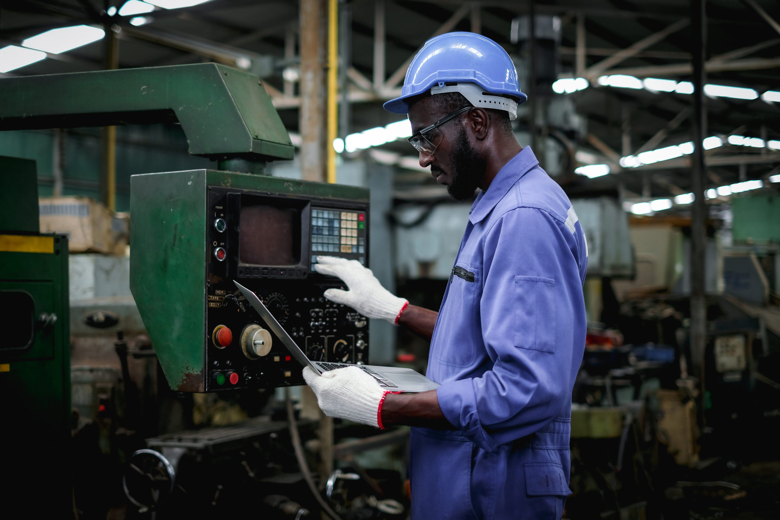 Factory worker using laptop and push buttons to test the machine ...